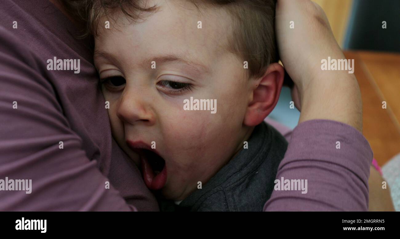 Tired child yawning exhausted kid yawns on mother lap Stock Photo - Alamy