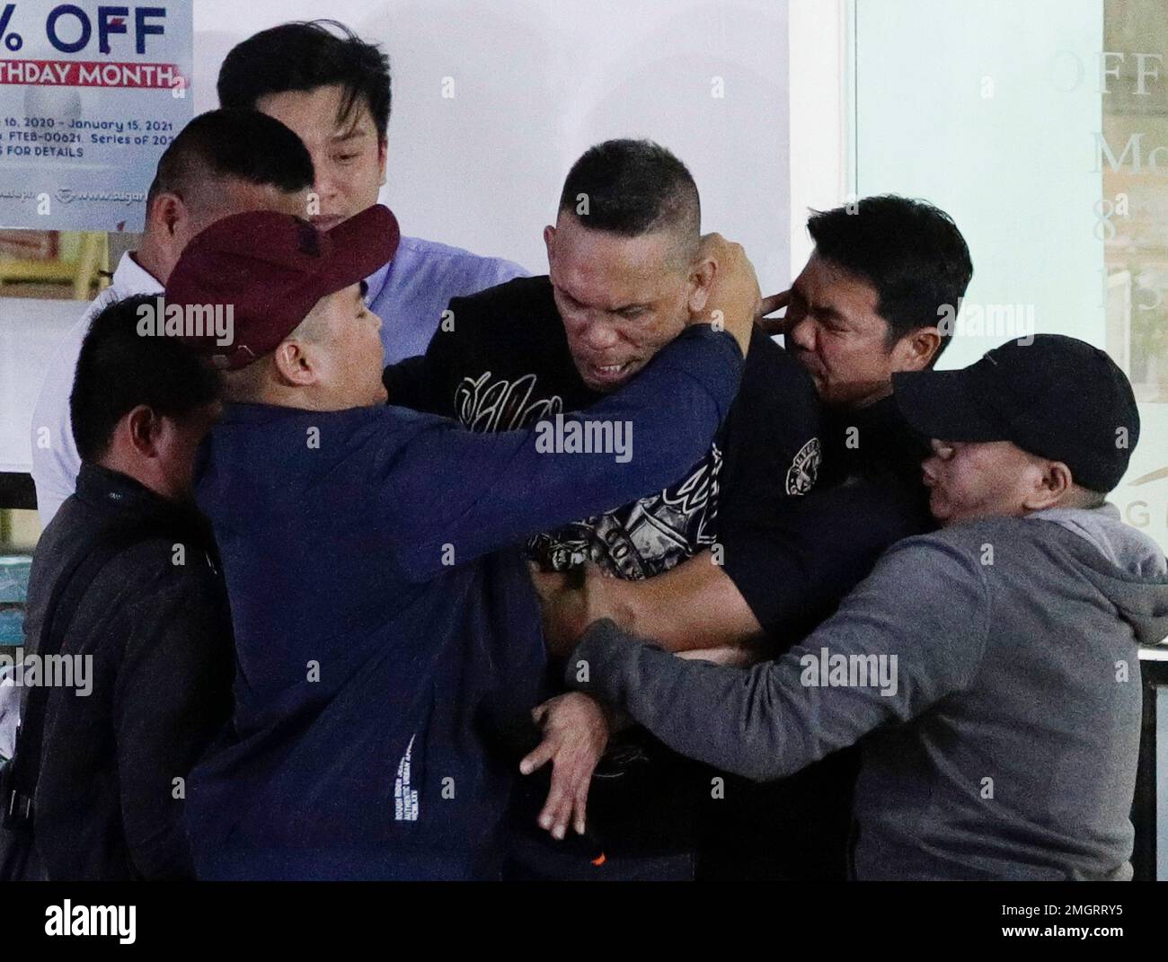 Former security guard Alchie Paray is restrained by police as he talks ...
