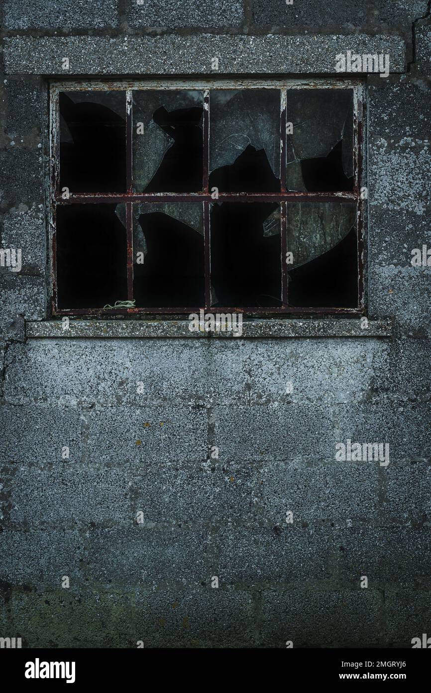 Broken windows and sharp glass set into a brick building. Portrait ...