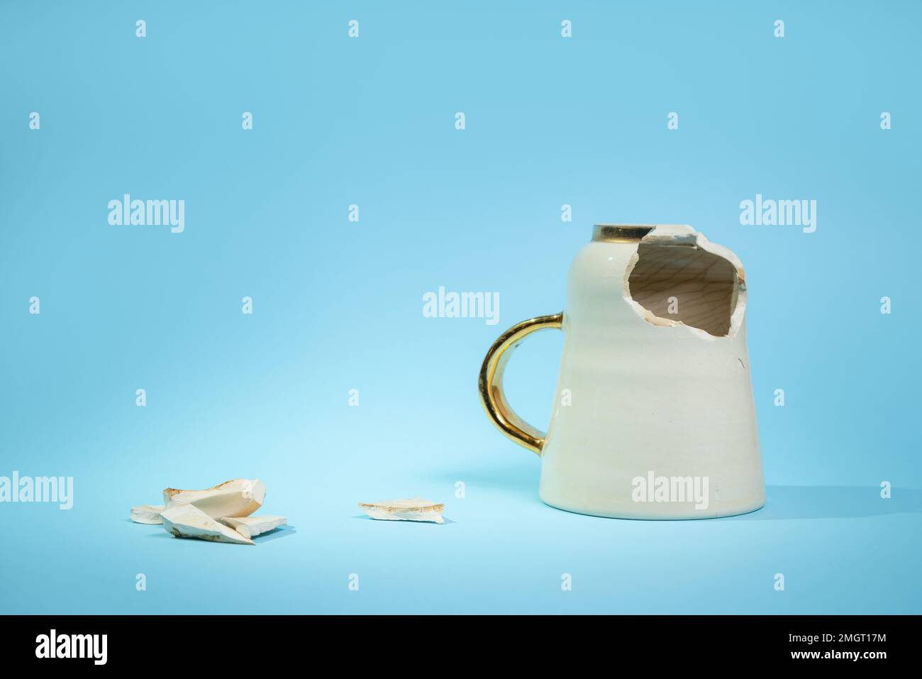 Broken tea cup isolated on blue background. Cracked coffee mug and ...