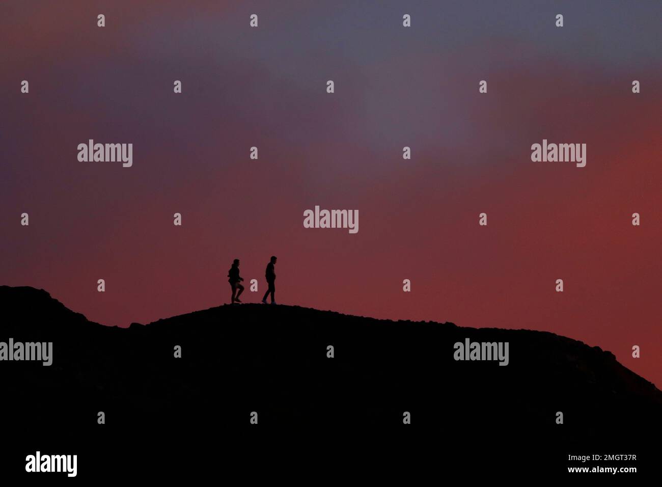 Hikers climb on rocks at Papago Park as the setting sun lights up ...