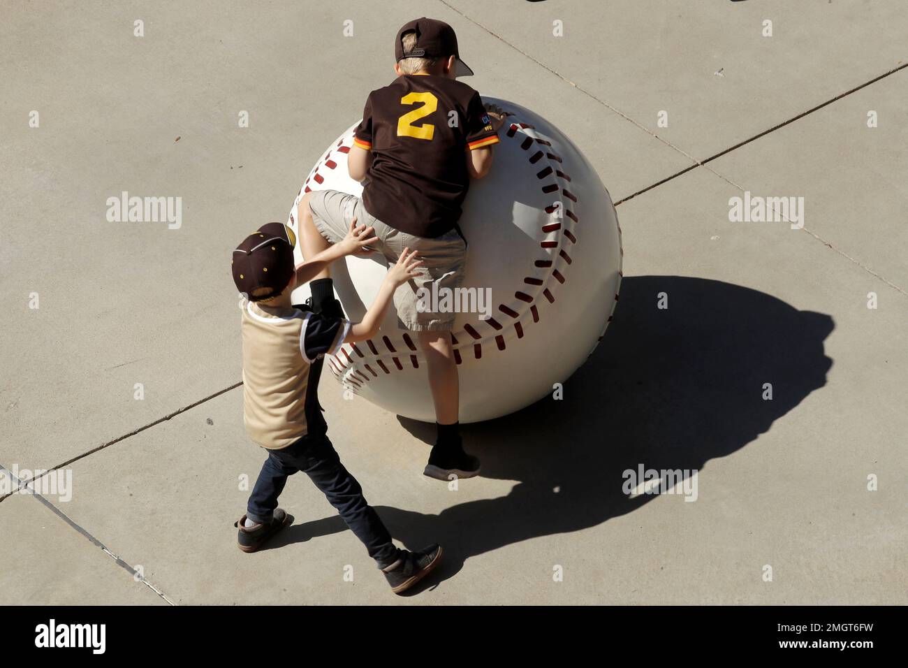 Two young San Diego Padres fans play on a concrete baseball before a ...