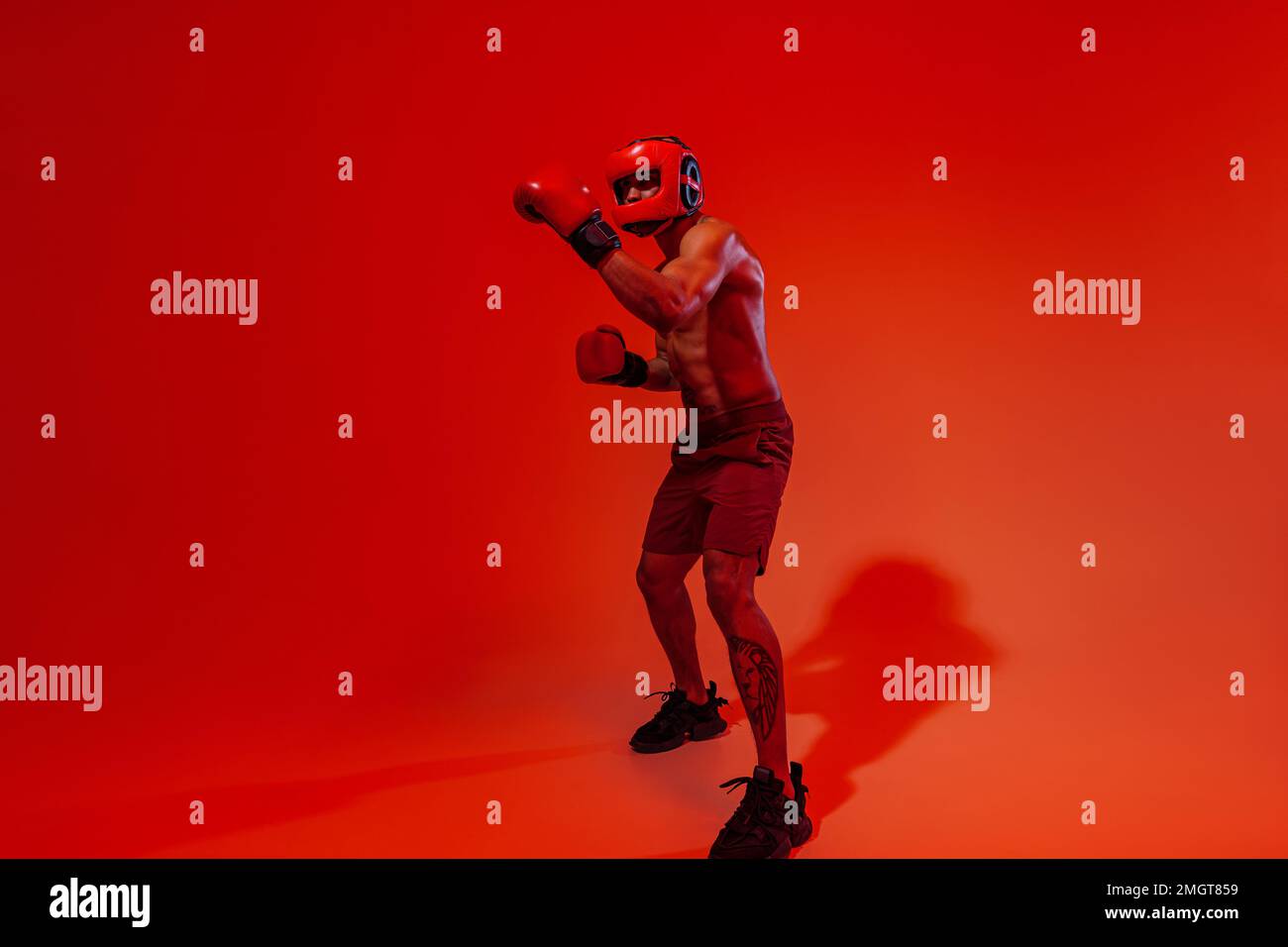 Sporty man wearing head guard and boxing gloves practicing for fight on ...