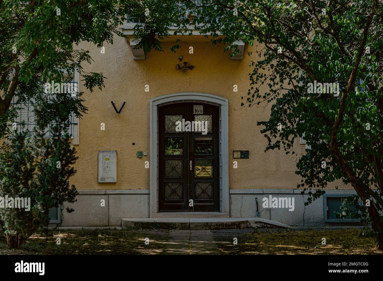 the doorway of an apartment building next to green vegetation in a ...
