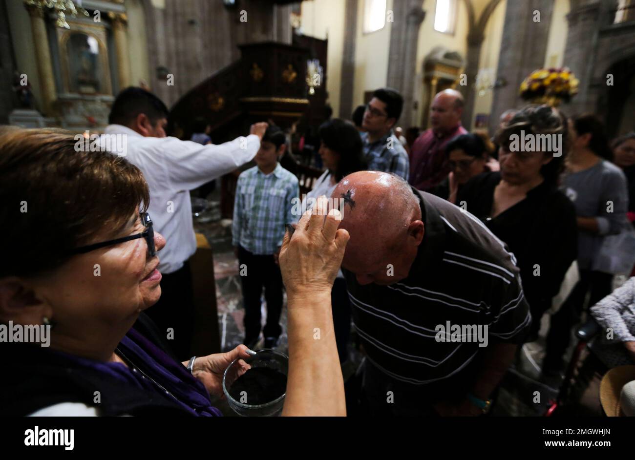 People line up to receive ashes on their foreheads and heads during a ...