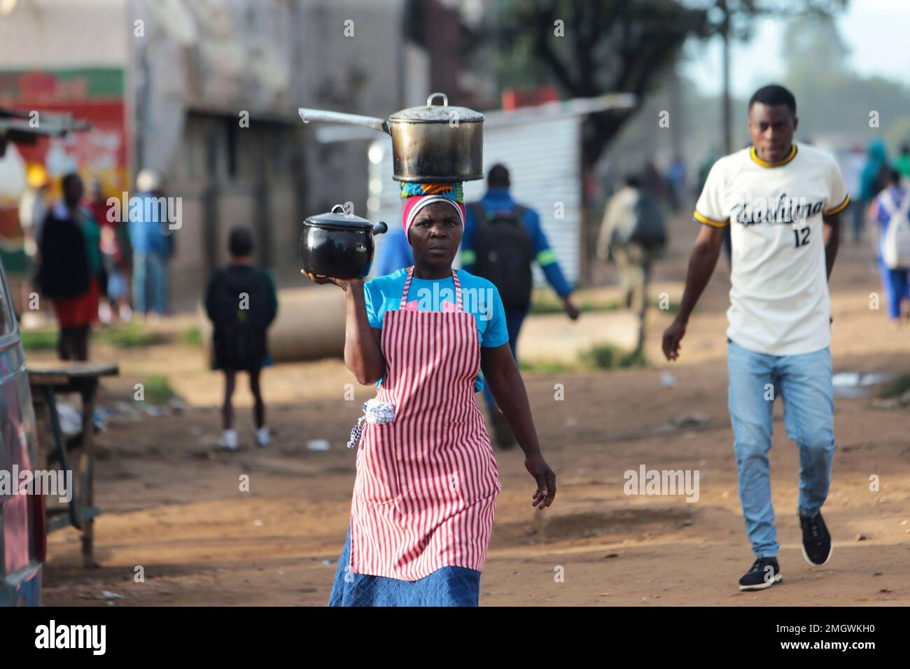 A woman carries a pot on her head while delivering food to a local ...