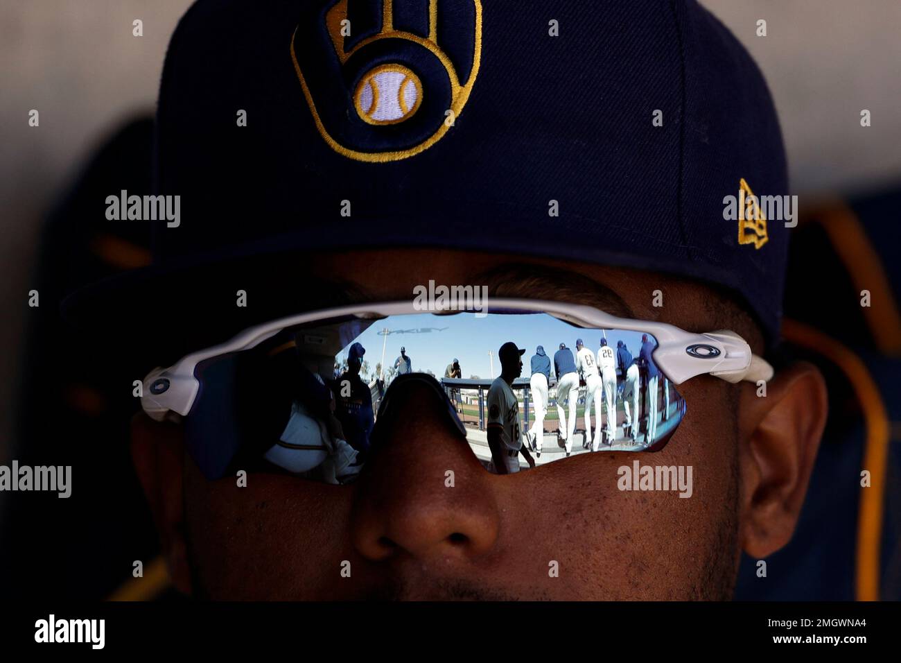 Milwaukee Brewers players in the dugout are reflected in the glasses of ...