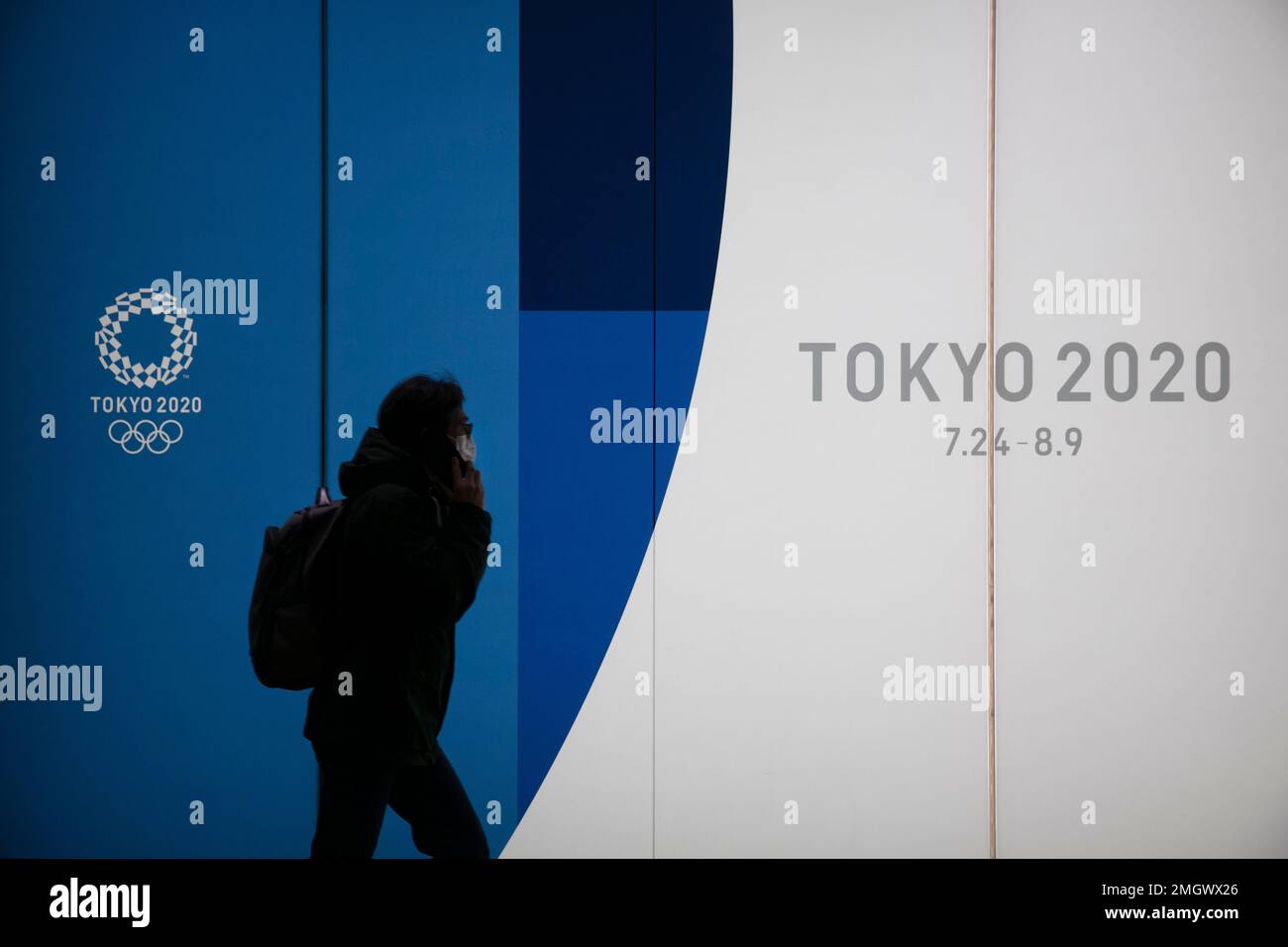 A man with a mask walks past a display promoting the Tokyo 2020 ...