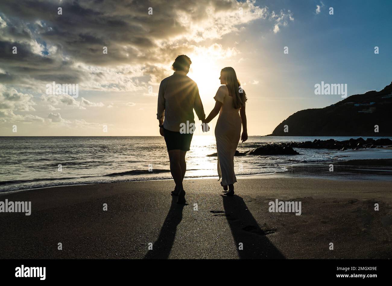 silhouette of young engaged couple holding hands in love during the ...