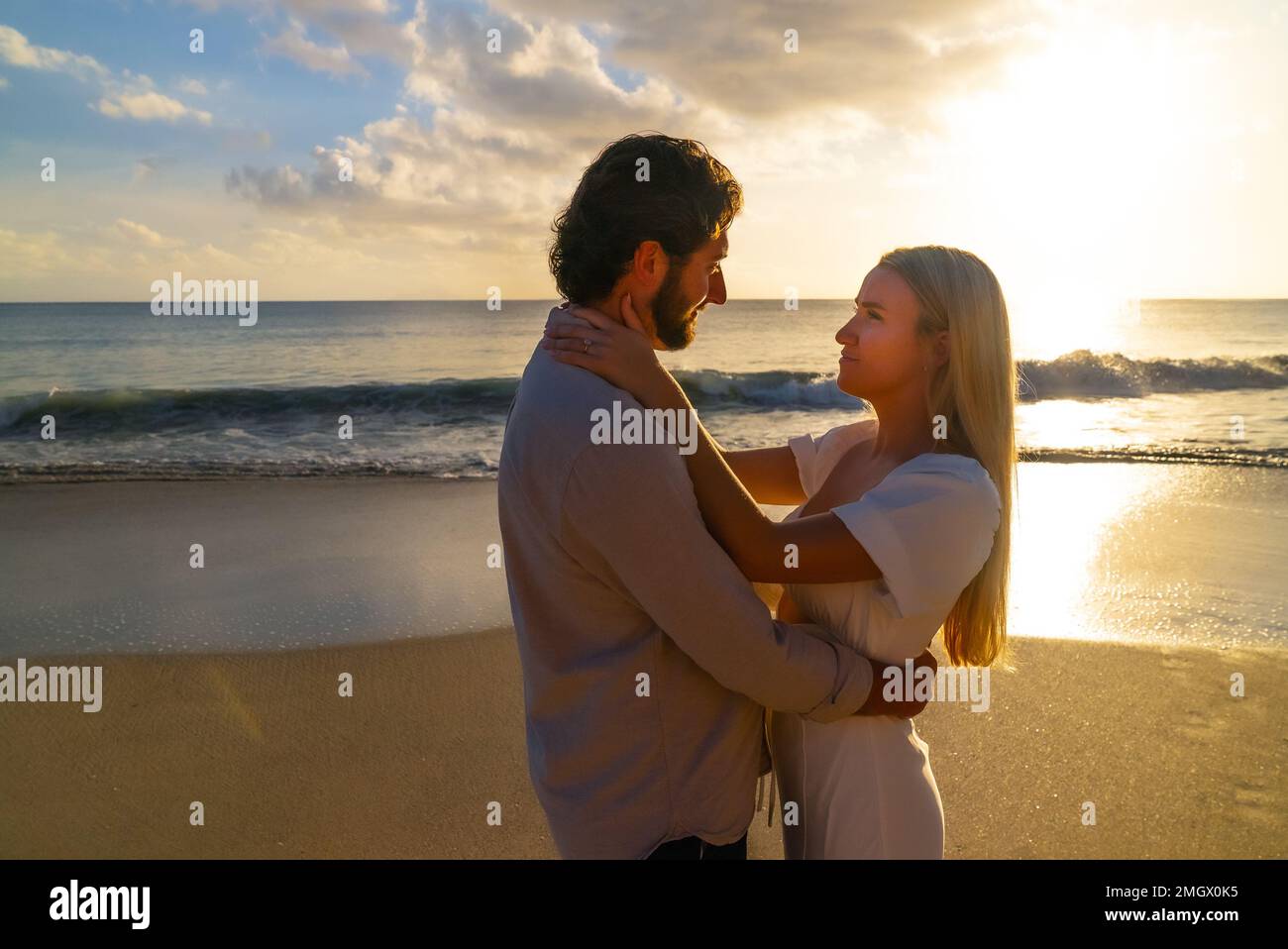 Newly engaged couple enjoying a romantic embrace during the golden hour ...