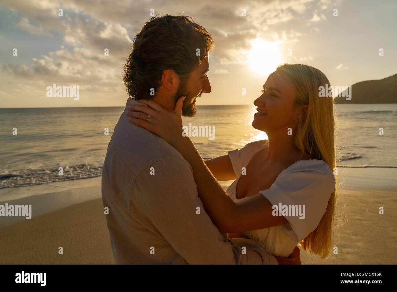 Newly engaged couple enjoying a romantic embrace during the golden hour ...