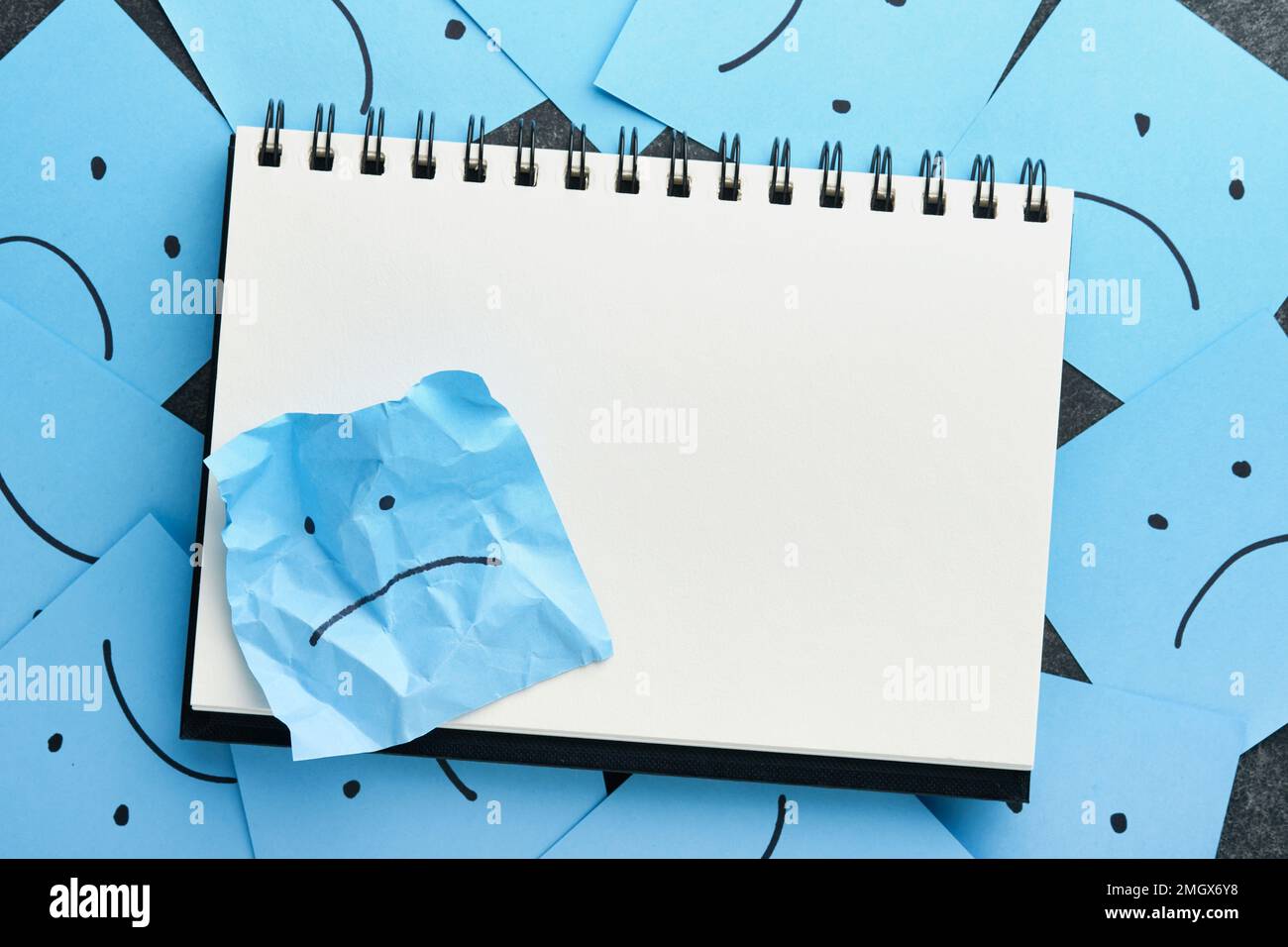 Blue crumpled sticky notes blank with drawing sad face on black ...