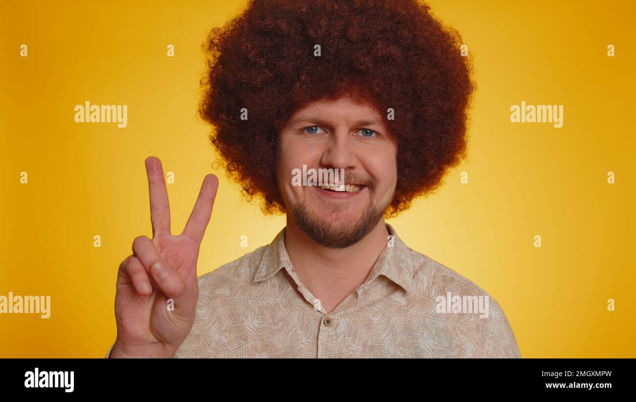 Bearded man with lush Afro hairstyle coiffure showing victory V sign ...