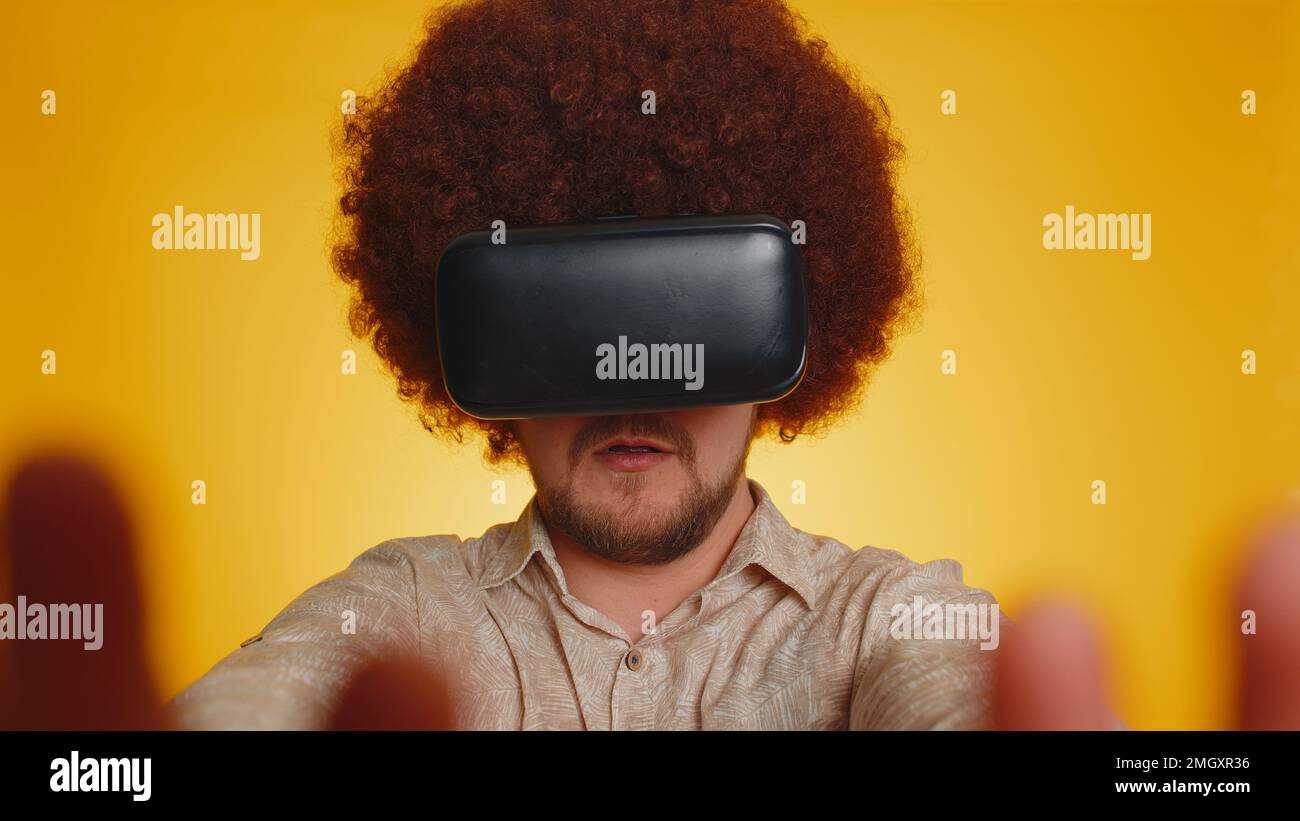 Redhead bearded man with lush afro hairstyle using headset helmet app ...