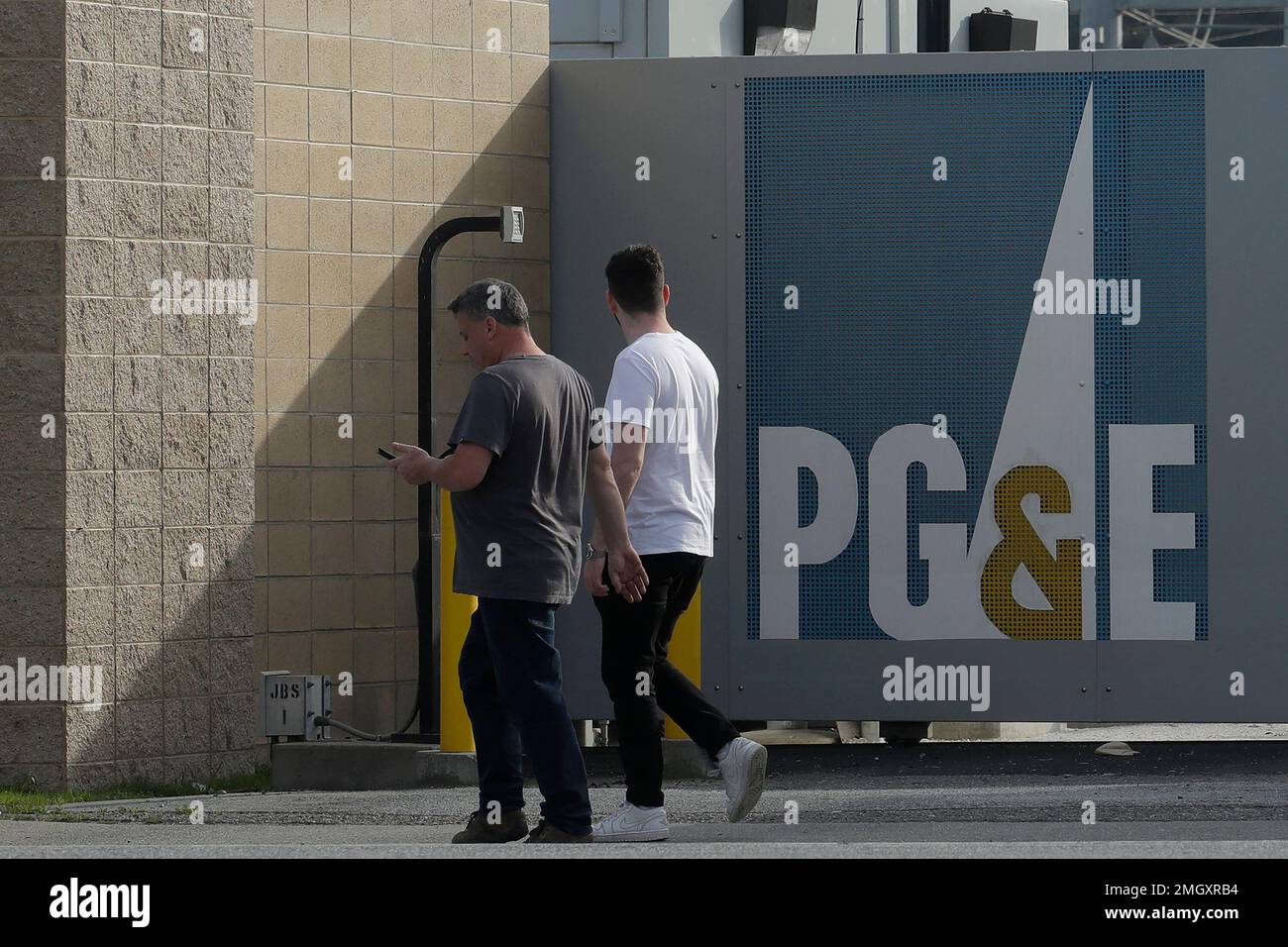Pedestrians walk past a Pacific Gas and Electric sign at a PG&E ...
