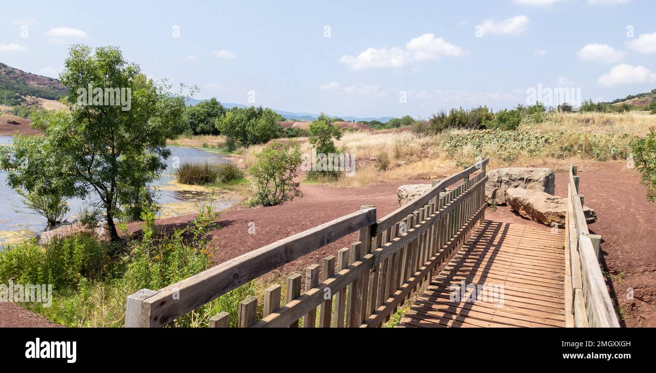 Red coloured coast lake deposits clay-like sediments and wooden bridge ...