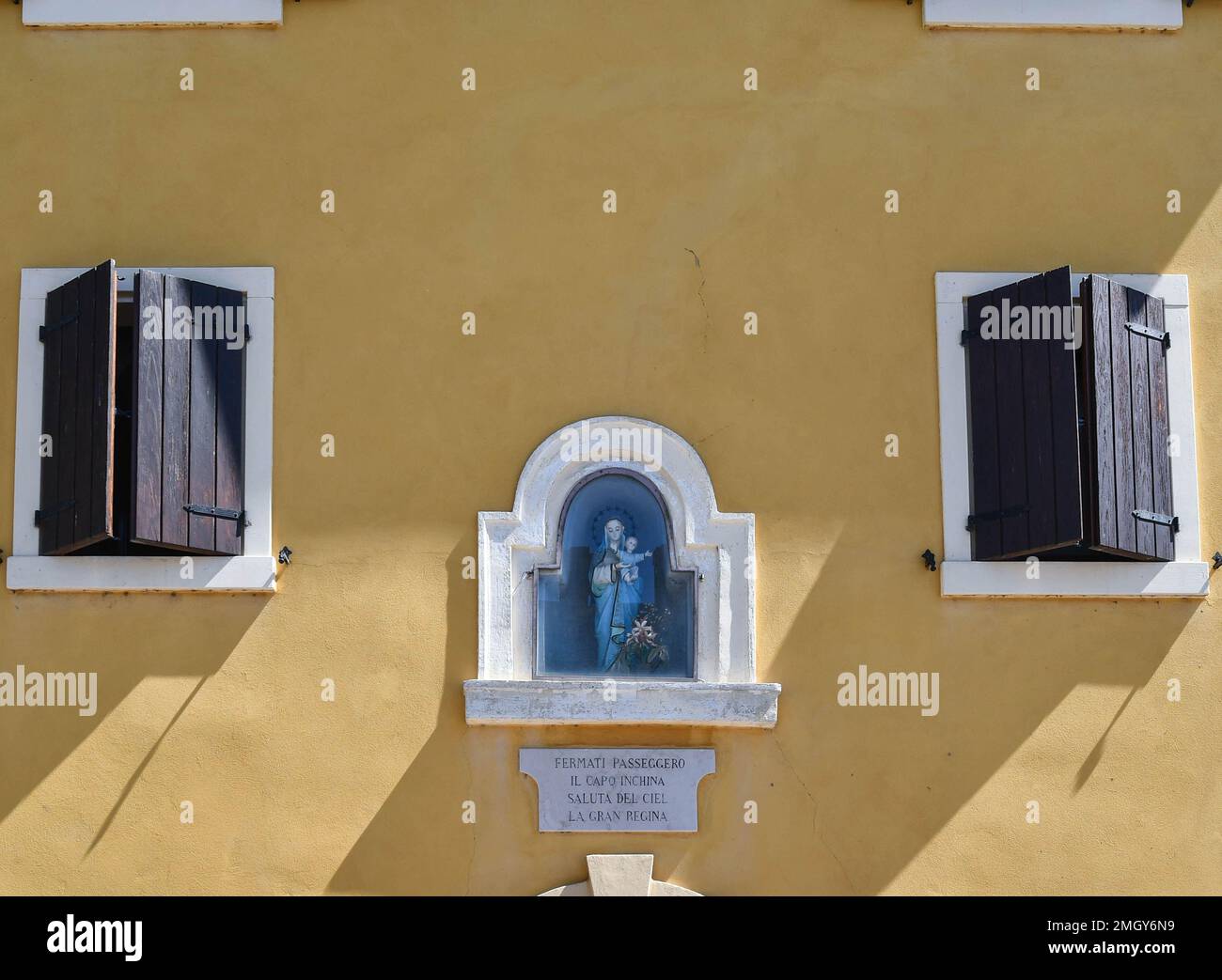Votive shrine with a statuette of St Mary and Baby Jesus on the facade ...