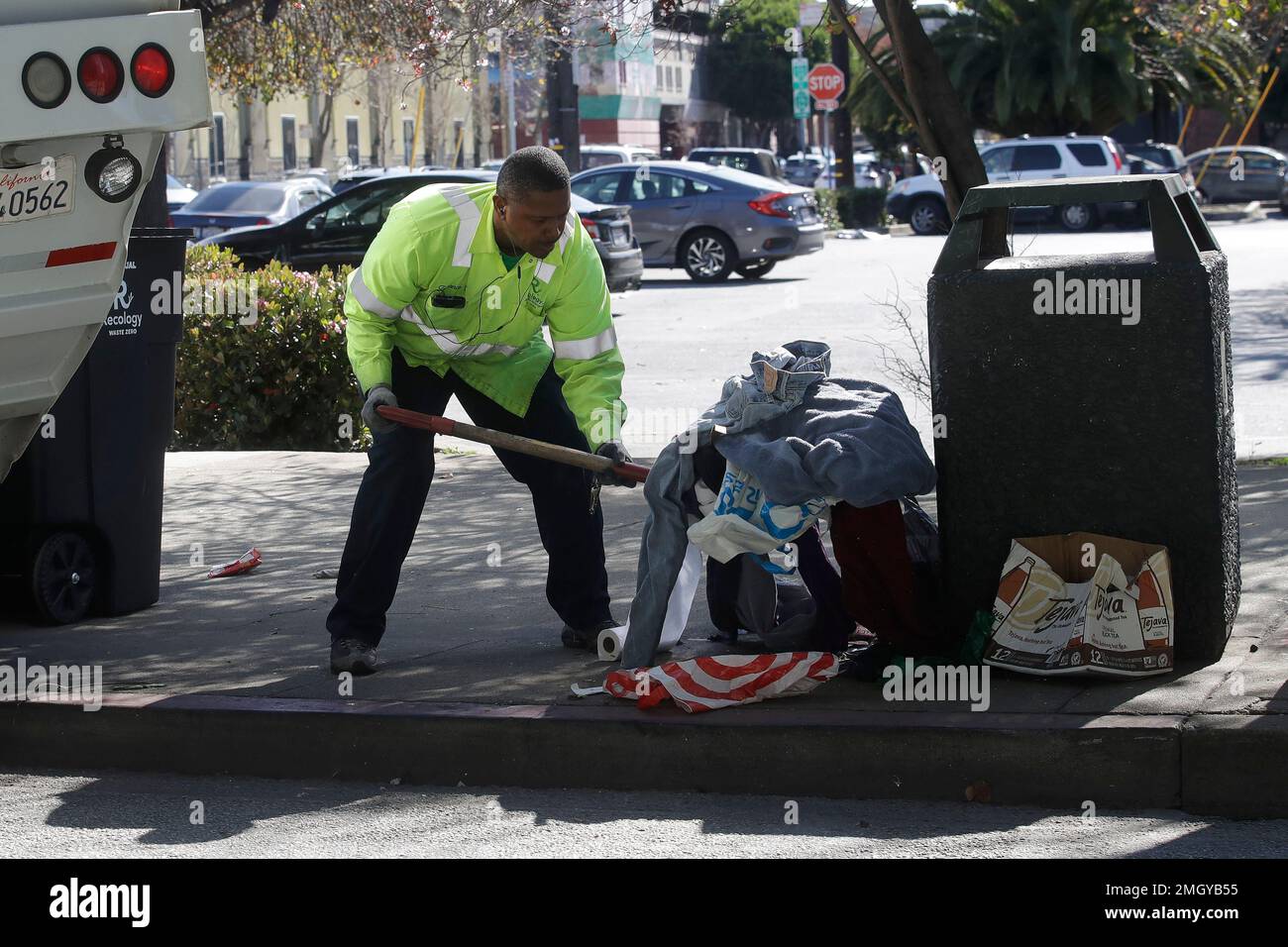 A Recology San Francisco worker picks up clothing and bags next to a ...