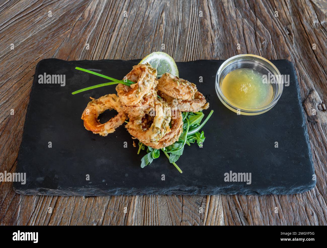 Fried squid rings with arugula, lemon salad and spicy appetizer sauce ...