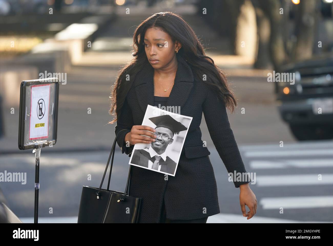 Zipporah Kuria, of London, carries a photo of her deceased father Joseph Waithaka as she walks ...