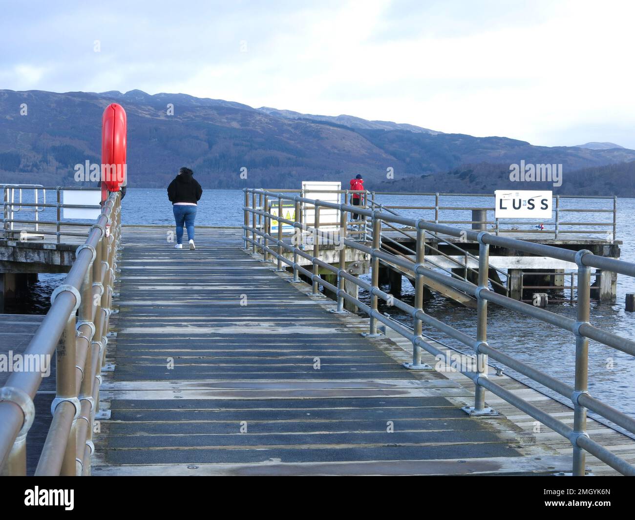 Hunched up against the cold, a single visitor walks down the pier at ...