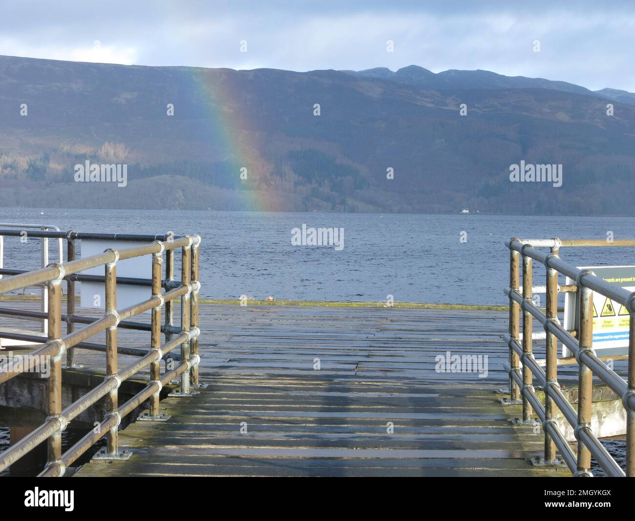 A rainbow shines in the winter sunlight at the end of the pier at Luss ...