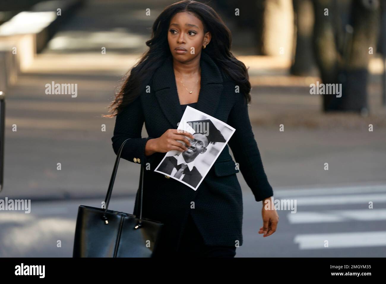 Zipporah Kuria, of London, carries a photo of her deceased father Joseph Waithaka as she walks ...