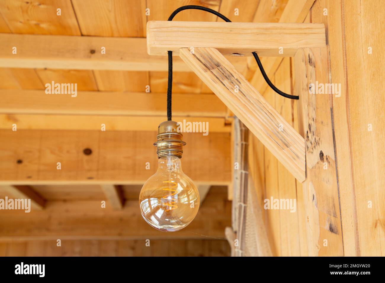 Vintage incandescent light bulb illuminates on wooden wall room ...
