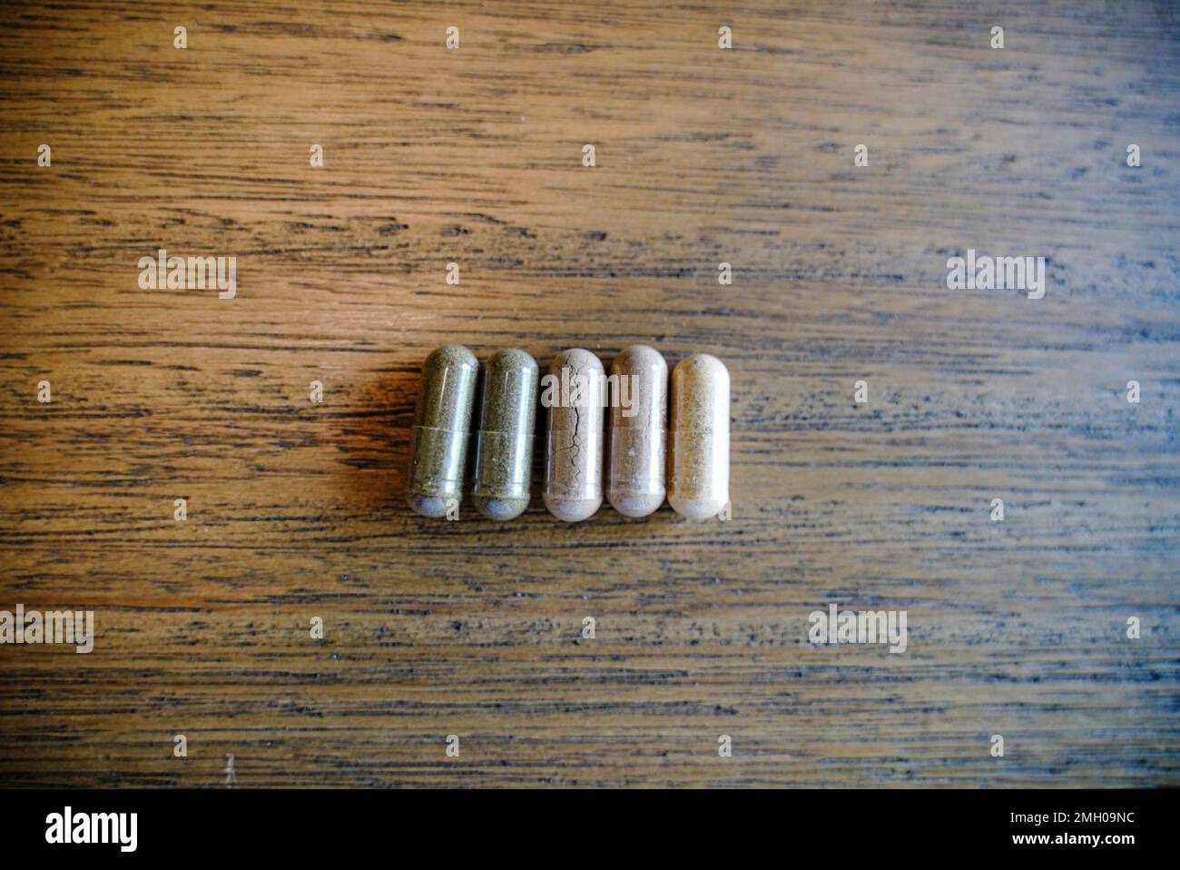 Medication Capsules Lined Up On Wood Table Stock Photo - Alamy