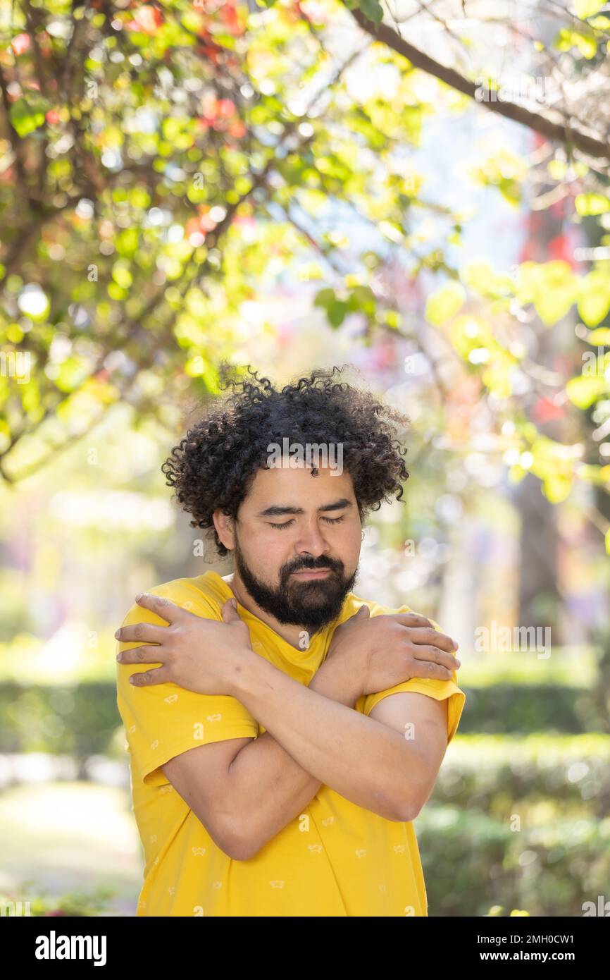 young Mexican man with beard and afro hugging himself, self love Stock ...