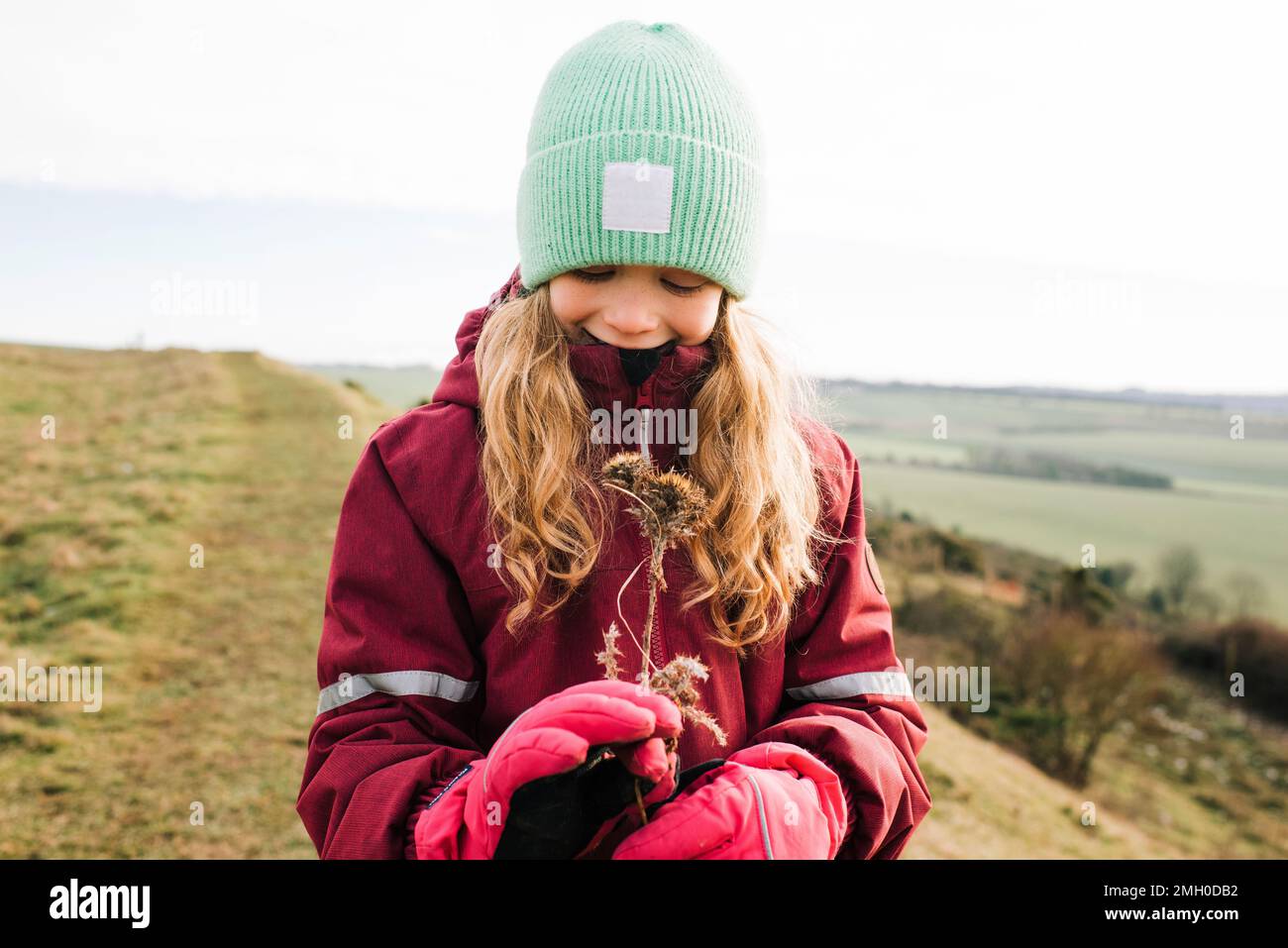 Girl smiling holding a thistle whilst walking the English countryside ...