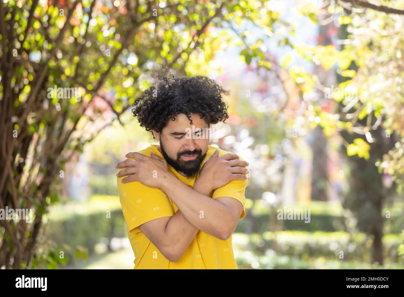 young Mexican man with beard and afro hugging himself, self love Stock ...