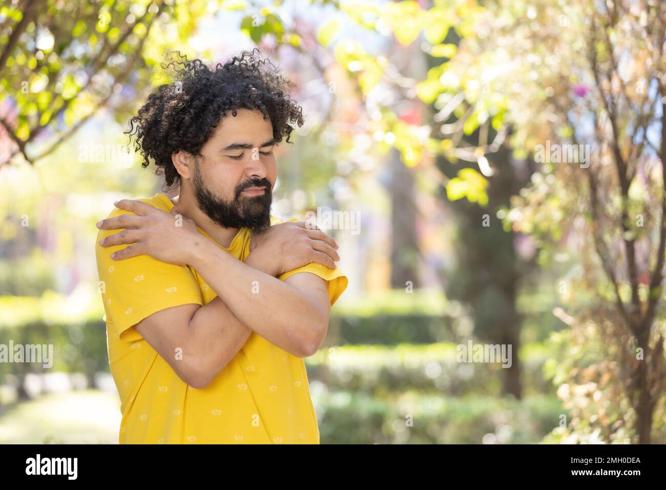 young Mexican man with beard and afro hugging himself, self love Stock ...