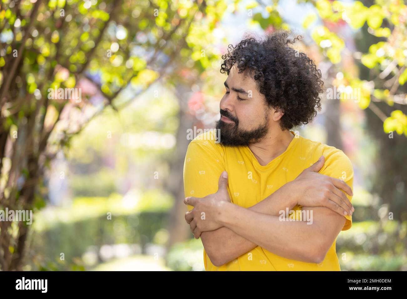 young Mexican man with beard and afro hugging himself, self love Stock ...
