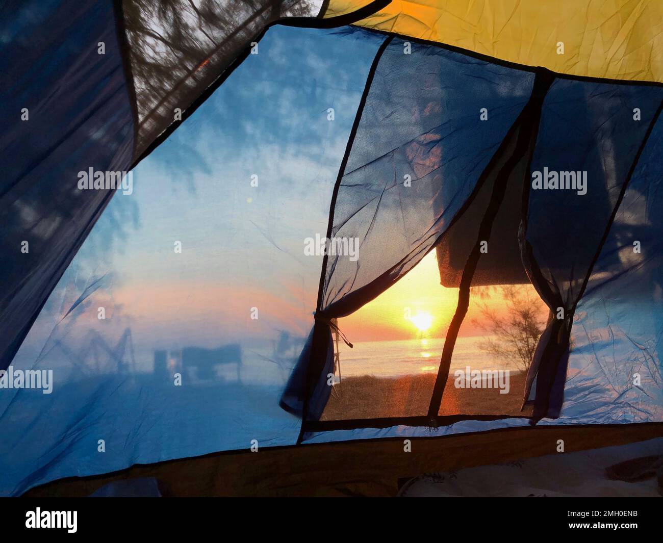 The morning sun rise is seen through a tent at a campsite in Wanakorn ...