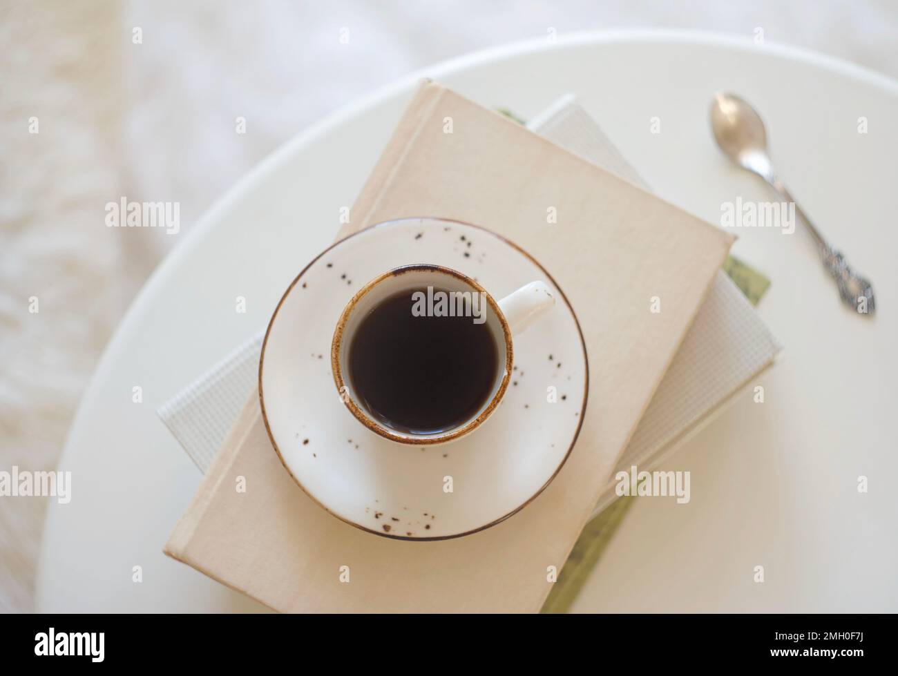 A mug of black coffee stands on a stack of books on the table Stock ...