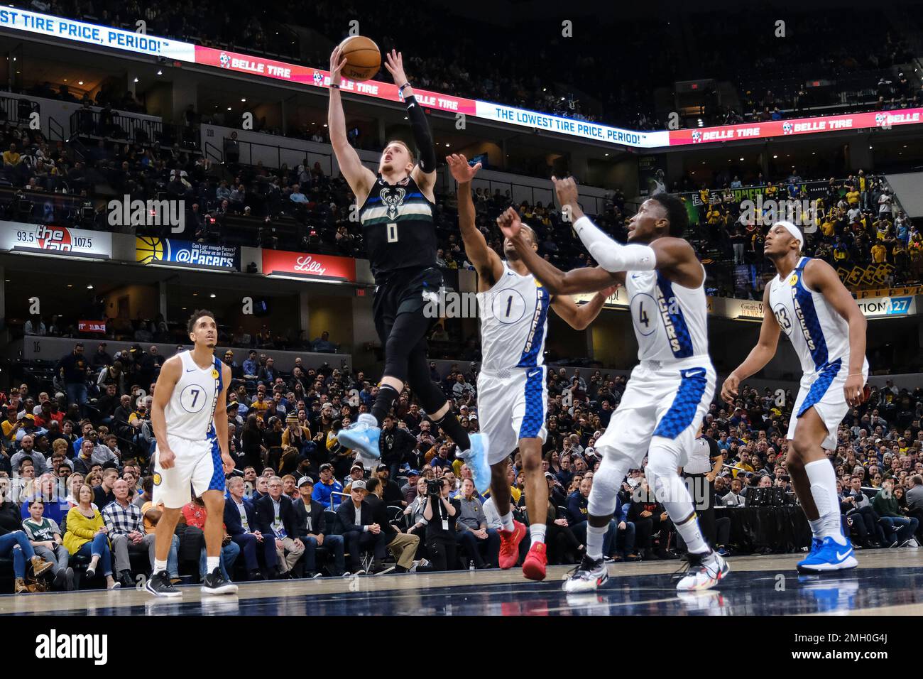 Milwaukee Bucks guard Donte DiVincenzo (0) shoots in front of a group ...