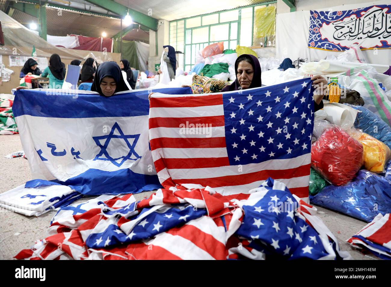 In this Saturday, Feb. 8, 2020 photo, workers fold U.S. flags and ...