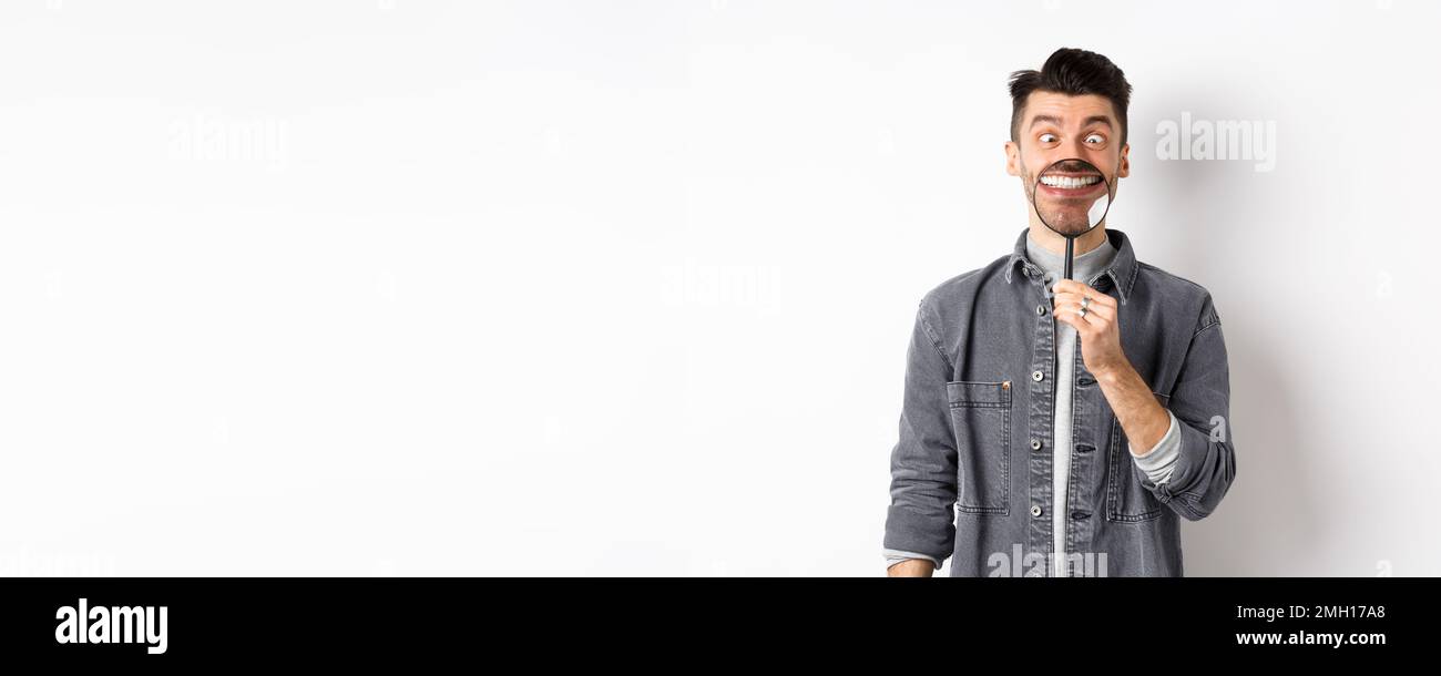 Handsome positive guy showing white perfect smile with magnifying glass ...