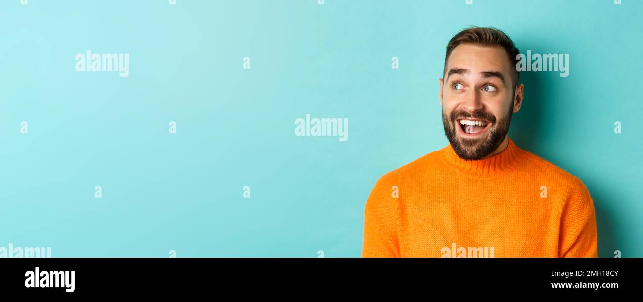 Close-up of handsome caucasian man smiling, looking left with surprised ...