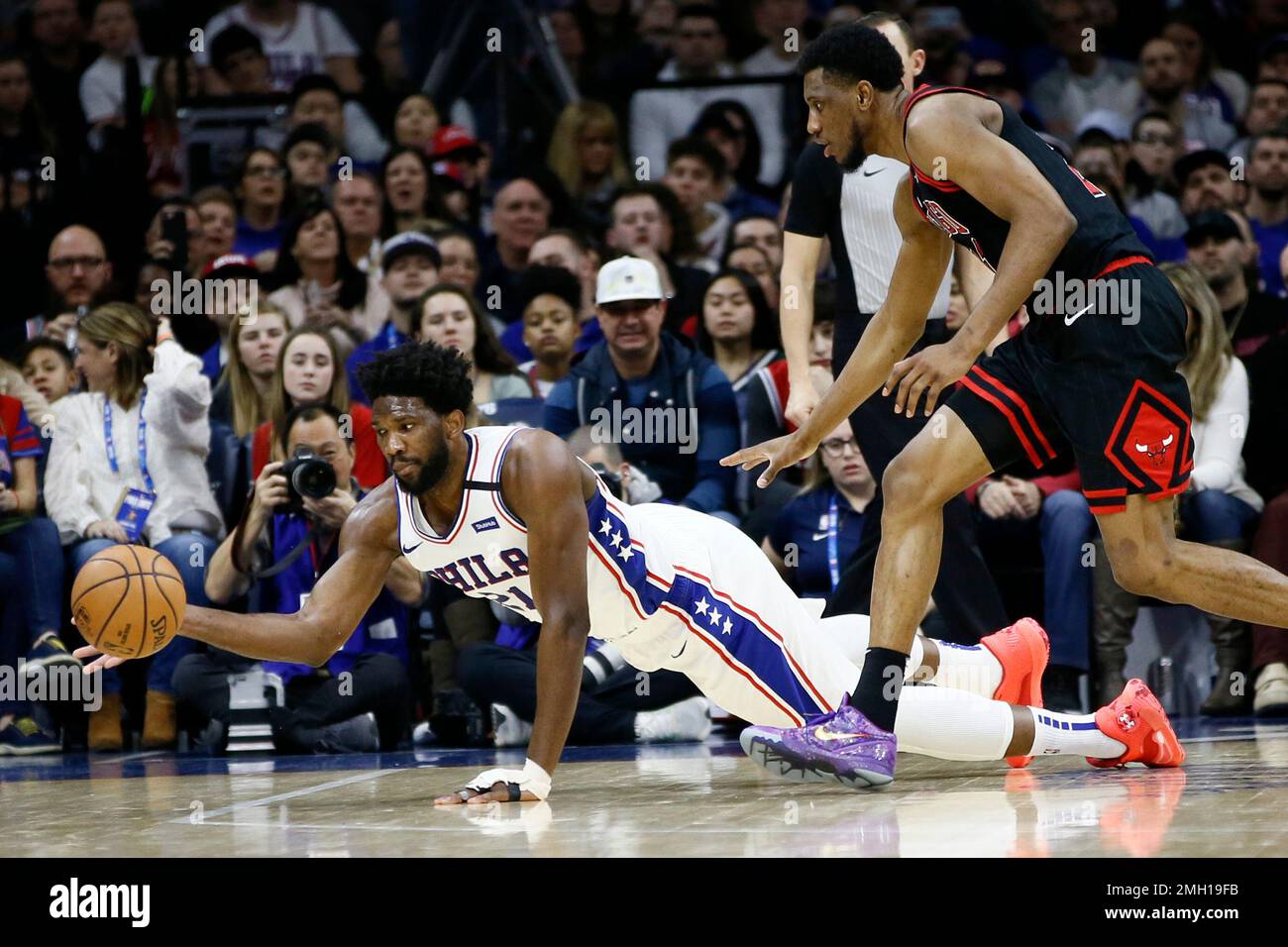 Philadelphia 76ers' Joel Embiid, left, dives for a loose ball past ...