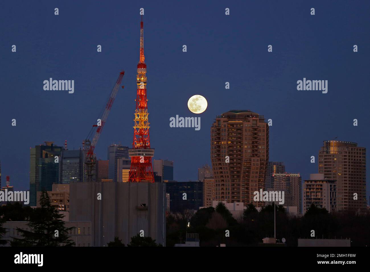 The rising full moon looms behind the Tokyo Tower Sunday, Feb. 9, 2020 ...
