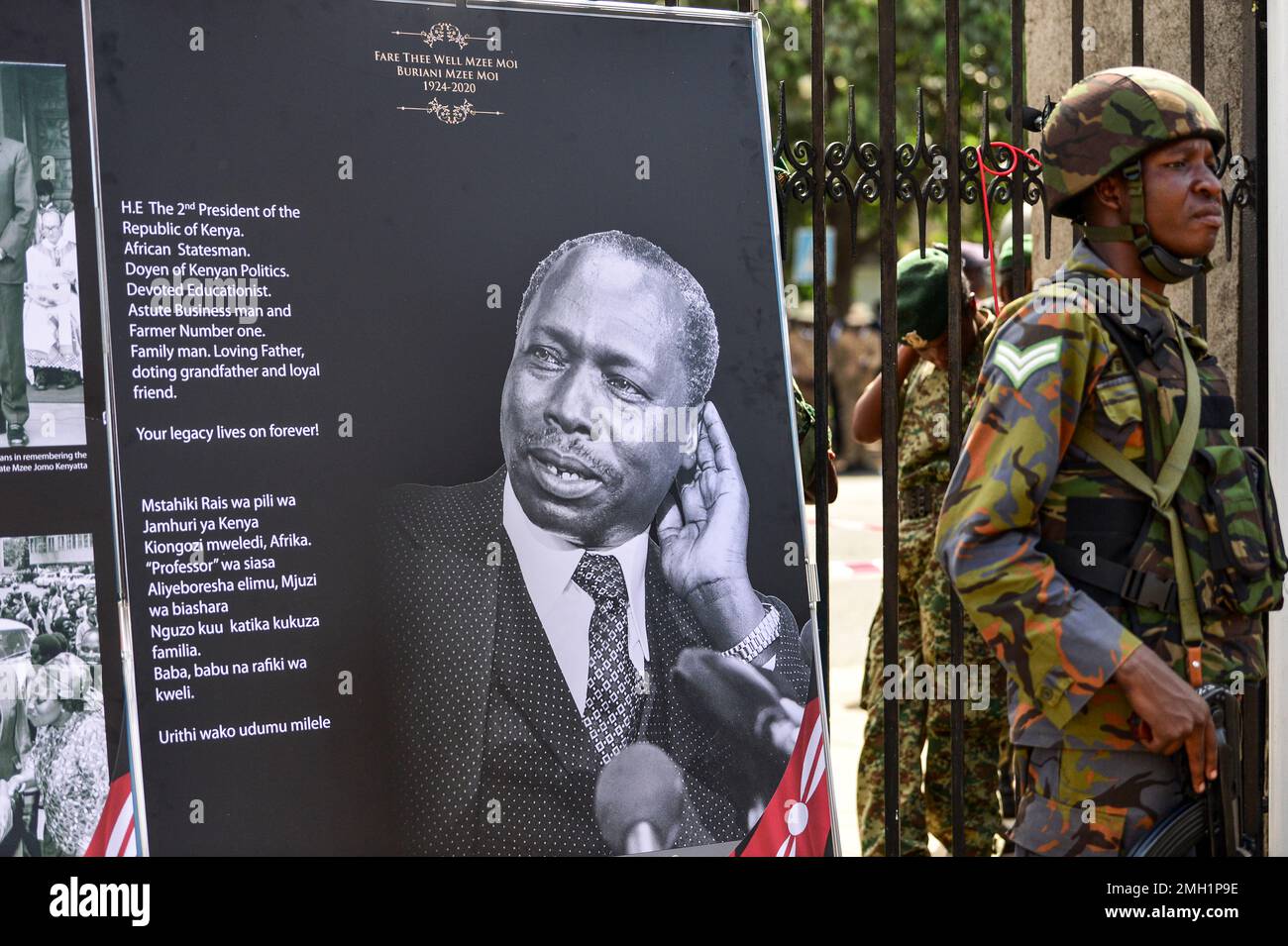 A Kenyan military officer stands by a memorial poster for former ...