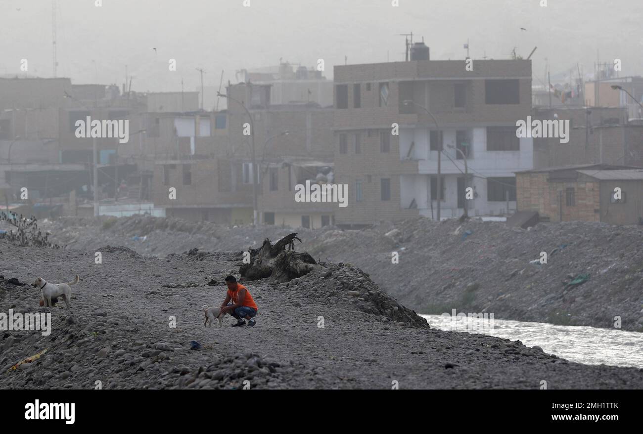 A man plays with his dog next to the Chillon River in Callao, Peru ...