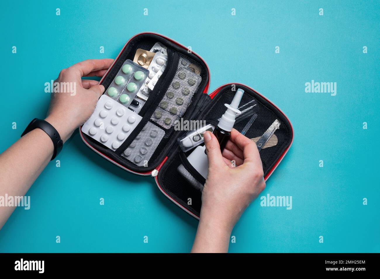 A woman opens a first aid kit. Home first aid kit on a blue background ...