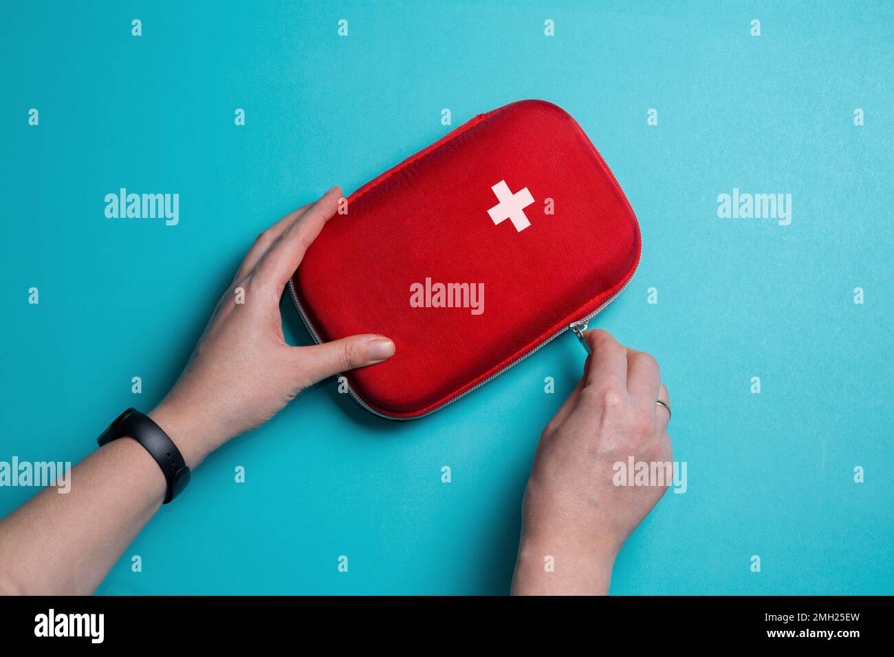 A woman opens a first aid kit. Home first aid kit on a blue background ...