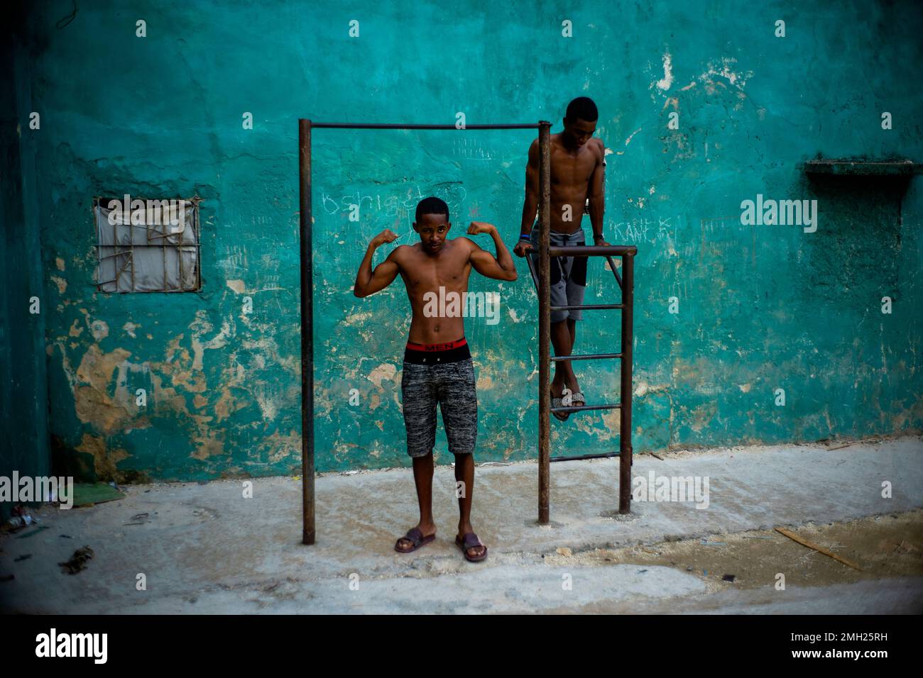 A young man strikes a pose showing off his muscles, framed by a pull up ...