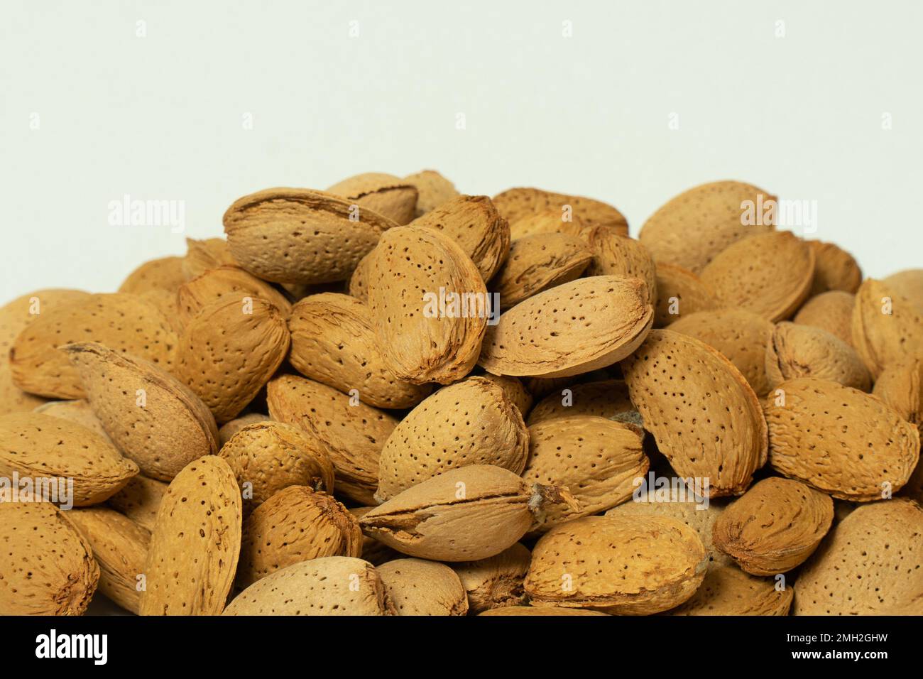 Whole almonds in shell closeup against white background Stock Photo - Alamy