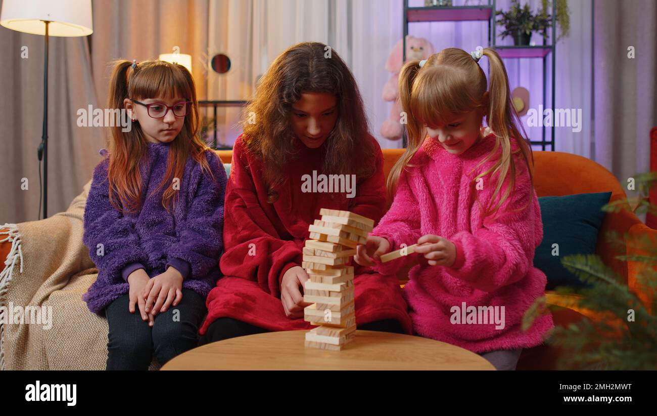 Teenage girl and toddler child sisters build tower from wooden bricks ...