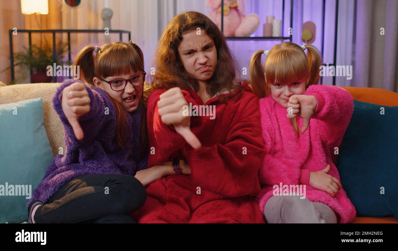 Dislike. Upset teenage child and little sisters kids show thumbs down ...